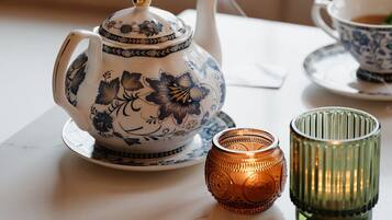 Uma mesa com um bule, xícaras e uma vela.
