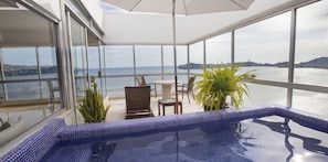 Uma varanda com vista para o mar, uma piscina pequena e mobiliário de exterior.