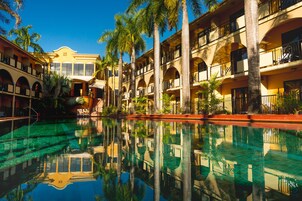 Hotel com piscina central que reflete palmeiras e arquitetura.