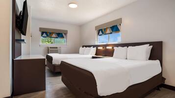 Quarto de hotel com duas camas, televisão de tela plana, escrivaninha e janela com vista.