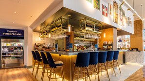 Uma área de bar com balcão, banquetas e um refrigerador de vinhos.