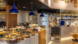 Cozinha moderna com bancadas de mármore, luminárias pendentes azuis e diversos alimentos expostos.