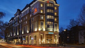 Um hotel com vários andares, um grande letreiro 'Marriott', amplas janelas e uma entrada de canto.