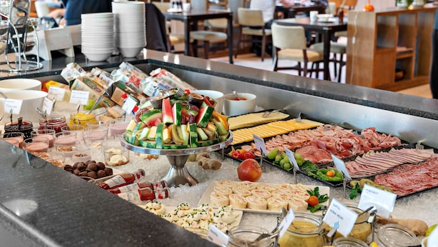 Buffet com diversos alimentos, incluindo frutas, queijos e carnes.