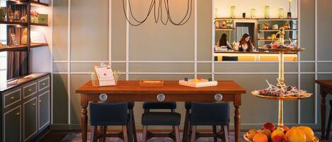 Uma sala de jantar com uma mesa de madeira, três cadeiras, um candelabro e uma exposição de frutas.