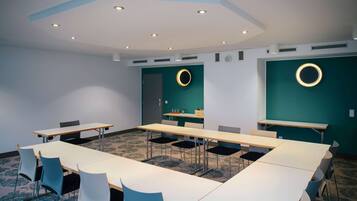 Uma sala de conferência com uma mesa comprida, cadeiras e piso coberto por carpete.