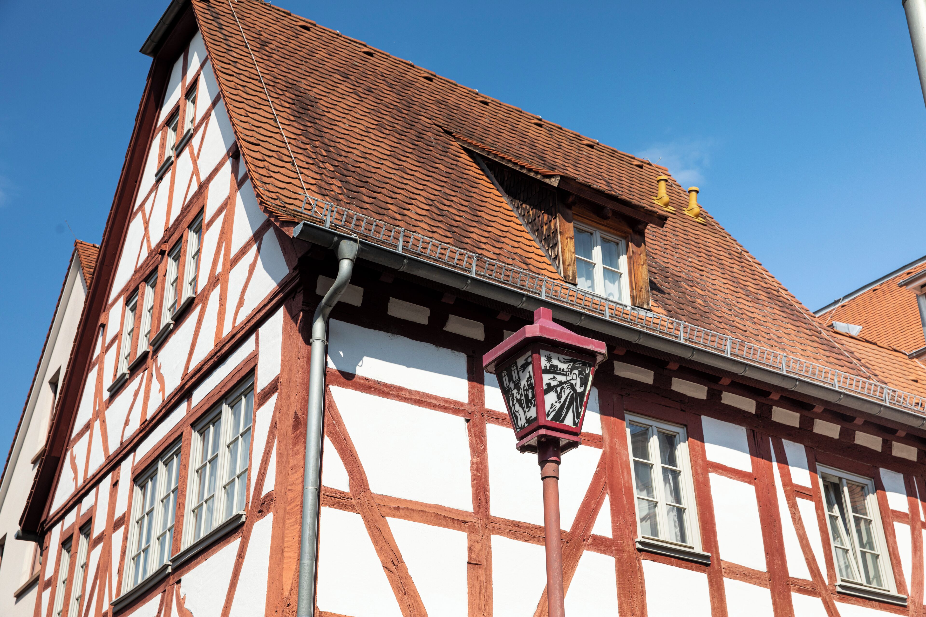 Um edifício em estilo meio-madeira com telhado íngreme e um lampião tradicional.