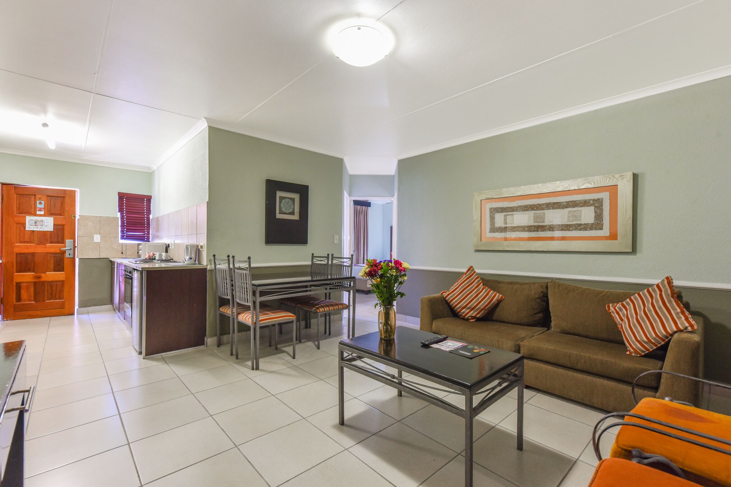 Uma sala de estar moderna com sofá, mesa de centro e área de jantar com cadeiras.