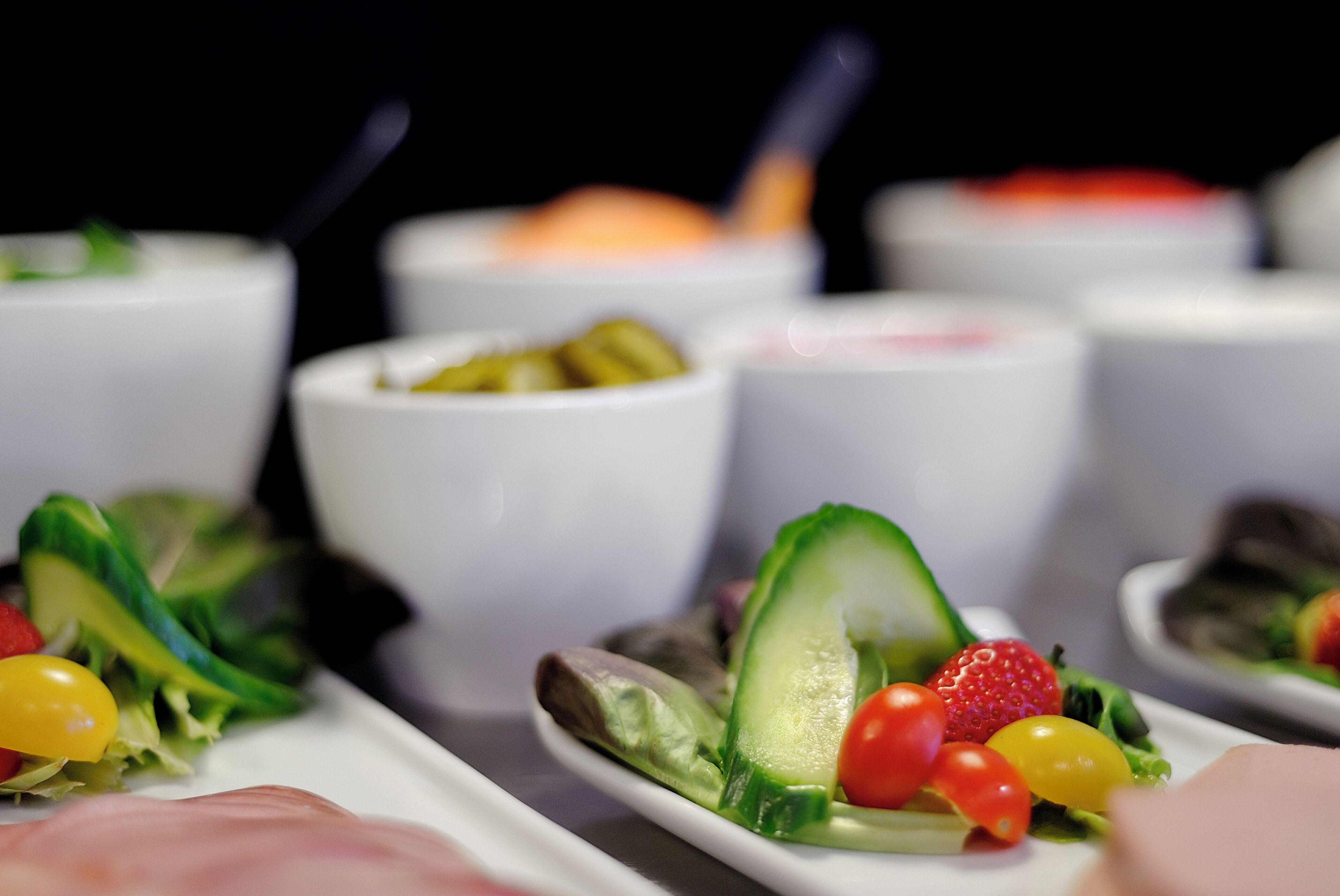 Diversos tipos de comida, incluindo saladas e patês, dispostos em pratos brancos.
