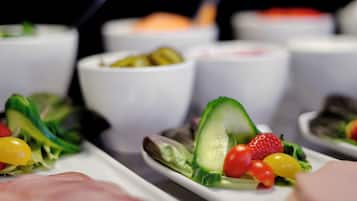 Diversos tipos de comida, incluindo saladas e patês, dispostos em pratos brancos.