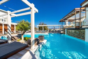 Uma área de piscina com espreguiçadeiras, um pérgola e vista para a paisagem.