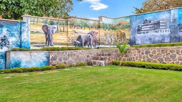 Um mural com animais selvagens numa parede de pedra, com uma área gramada na frente.