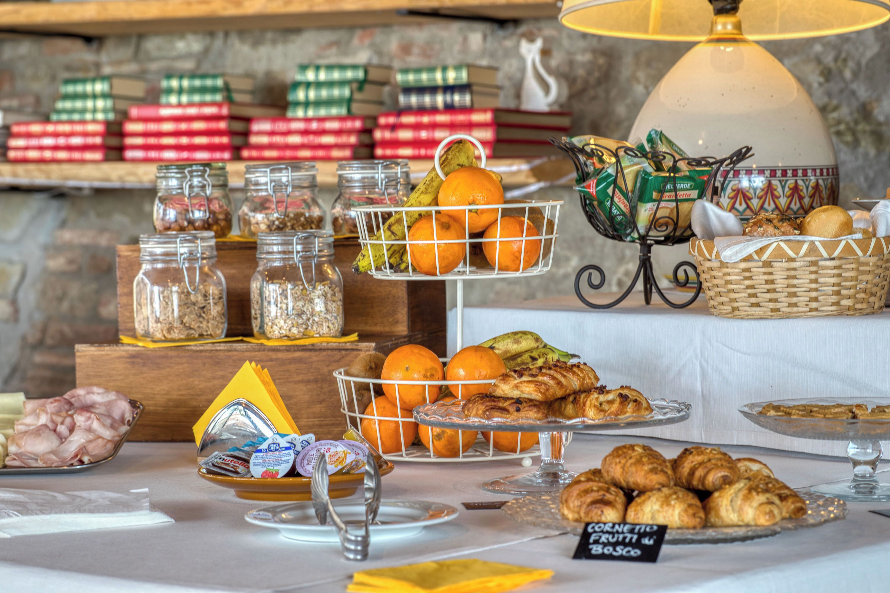 Mesa de buffet com diversos alimentos, incluindo frutas, doces e acompanhamentos.