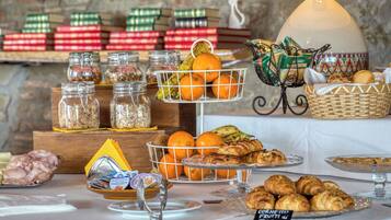 Mesa de buffet com diversos alimentos, incluindo frutas, doces e acompanhamentos.