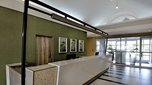 Uma área de recepção com balcão, obras de arte emolduradas e uma janela ampla.