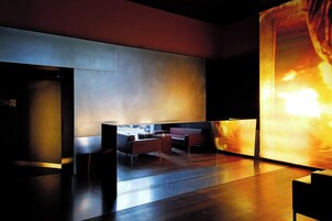 Um interior moderno com um sofá, mesa de centro e um grande painel iluminado.