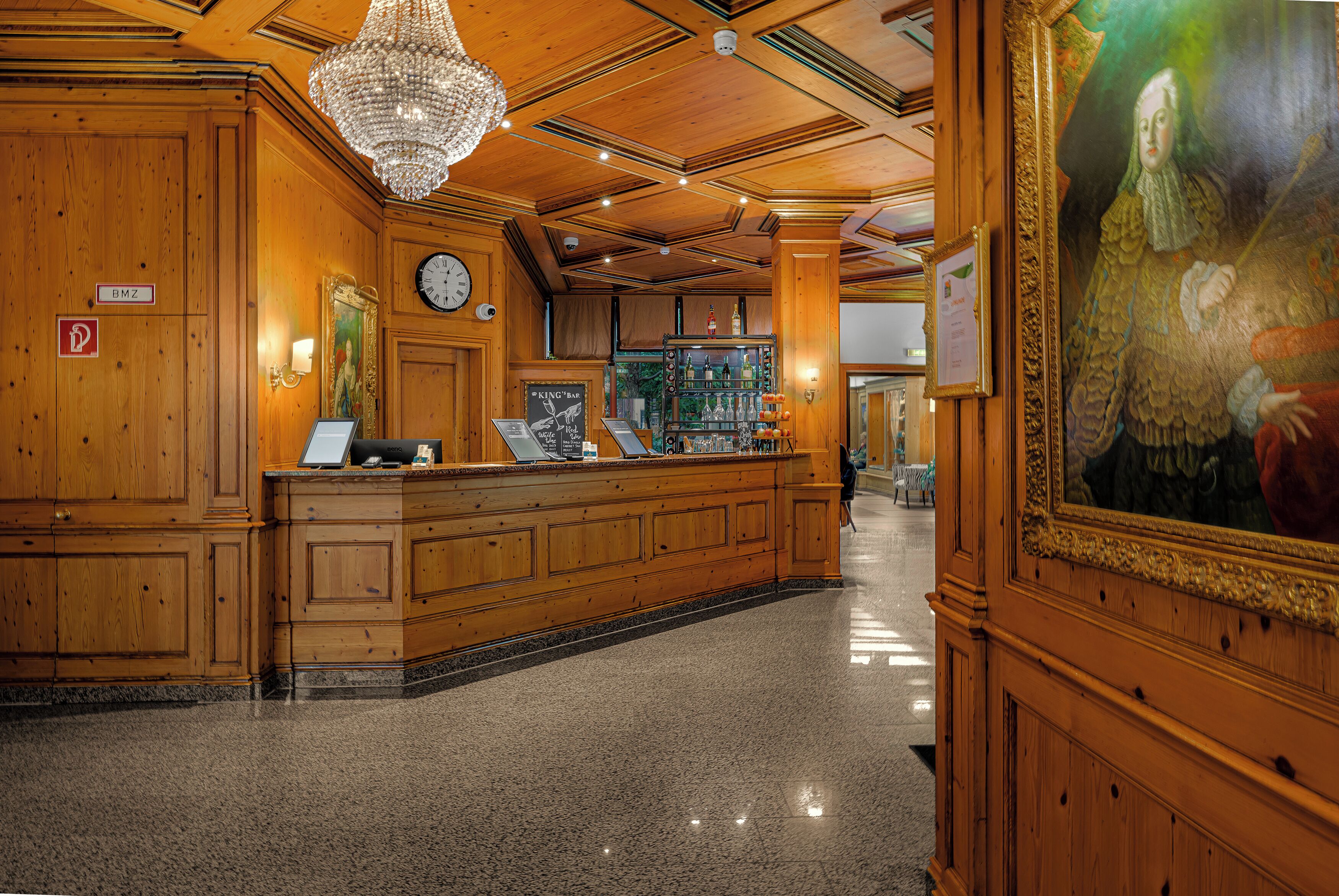 Um saguão de hotel com balcão de recepção, relógio e área de bar.