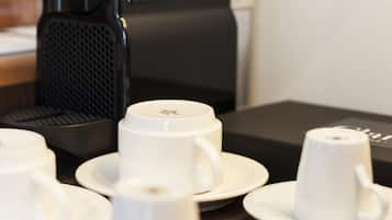 Uma máquina de café e várias xícaras brancas sobre uma mesa.
