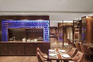 Um restaurante com parede de vinhos, mobiliário de madeira e um espaço de bar.