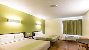 Quarto de hotel com duas camas, uma escrivaninha e uma janela com cortinas.