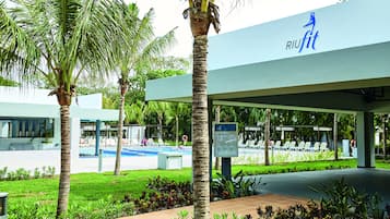Um hotel moderno com área de piscina, palmeiras e um espaço de estar coberto.