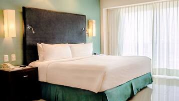 Quarto de hotel com uma cama grande, uma mesa de cabeceira com telefone e uma janela com cortinas.