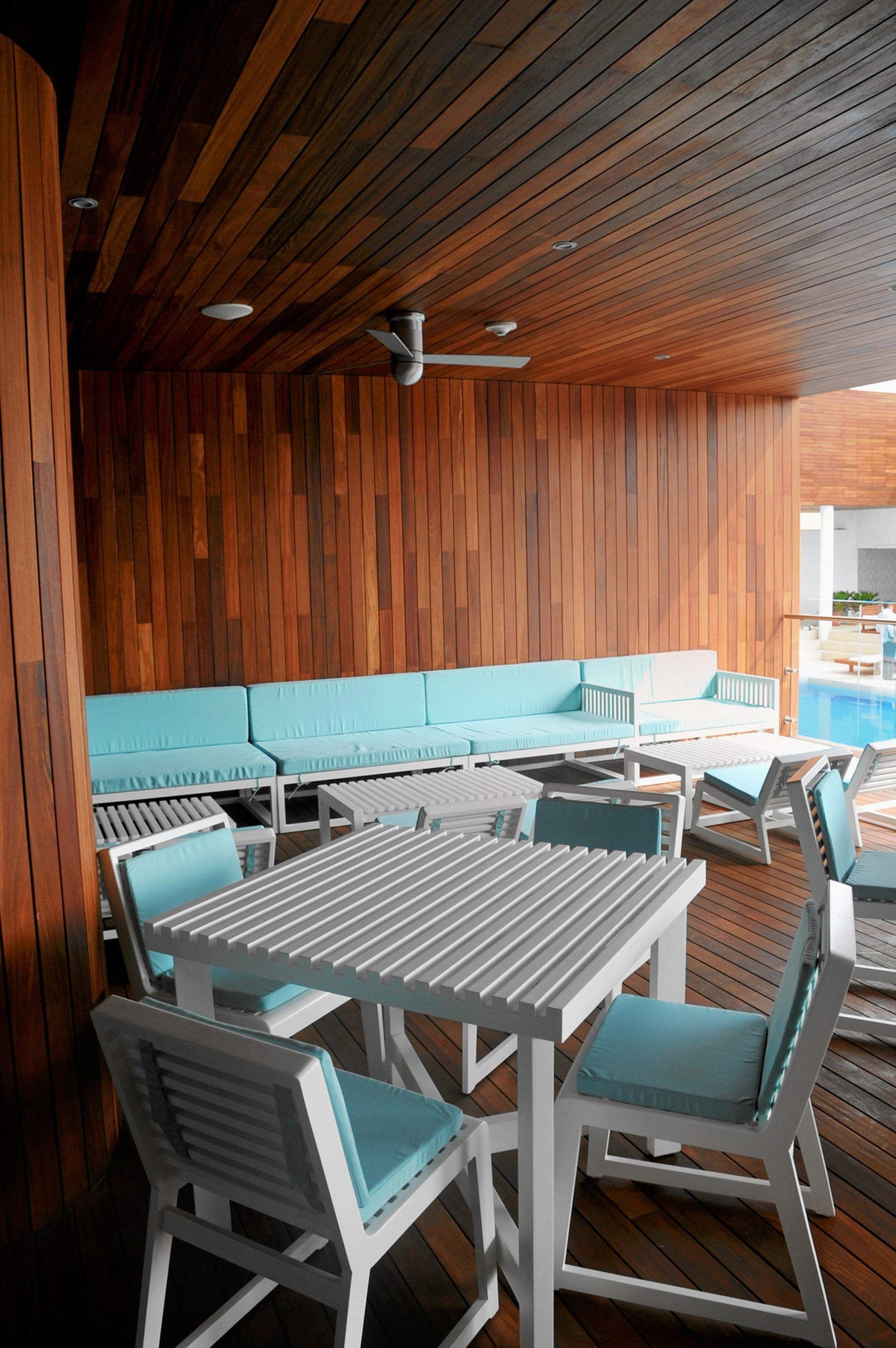 Um deck de madeira com piscina, móveis brancos e um ventilador de teto.