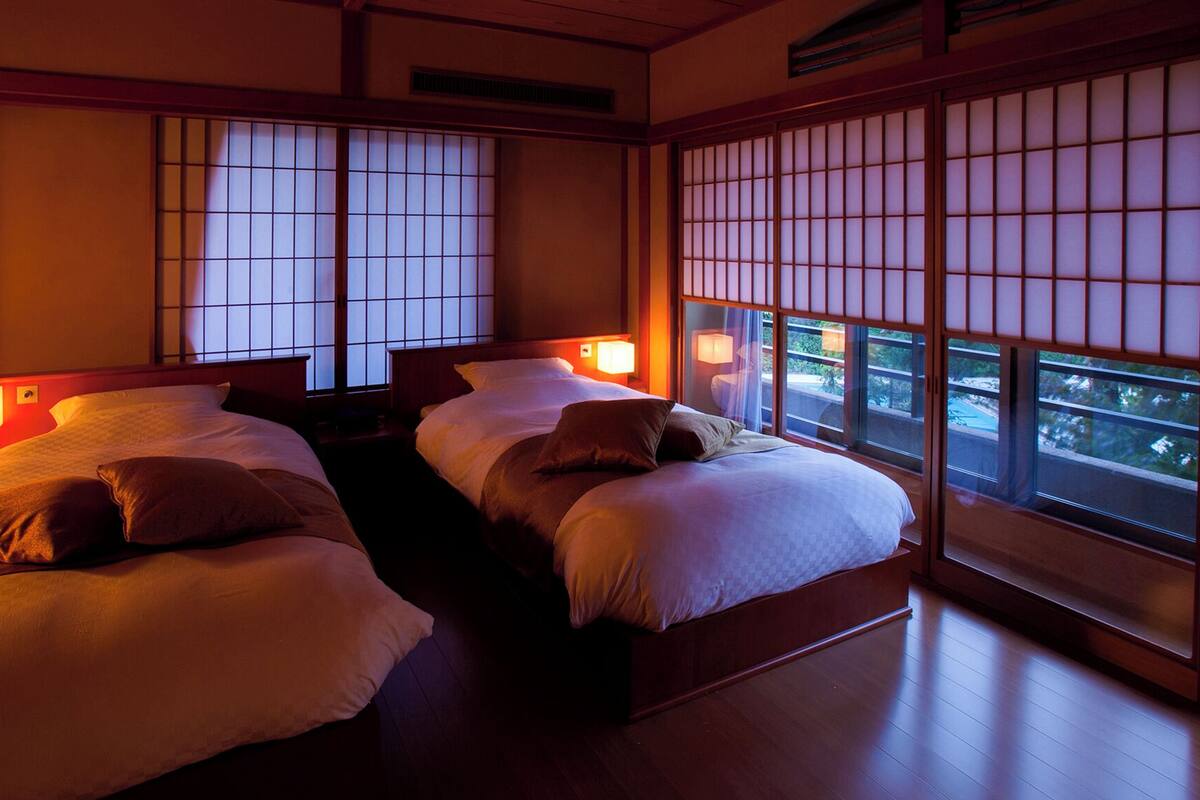 Quarto tradicional japonês com tatames, portas deslizantes shoji e vista para um jardim.