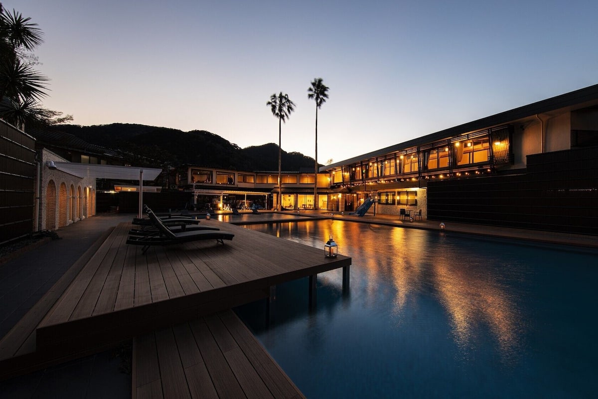 Um resort moderno com piscina, espreguiçadeiras e um deck coberto.