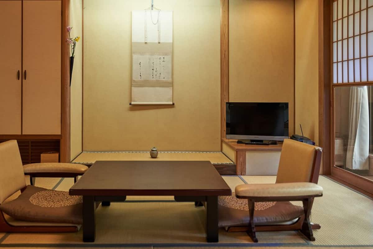 Um quarto japonês tradicional com tatames, uma mesa baixa e duas cadeiras.