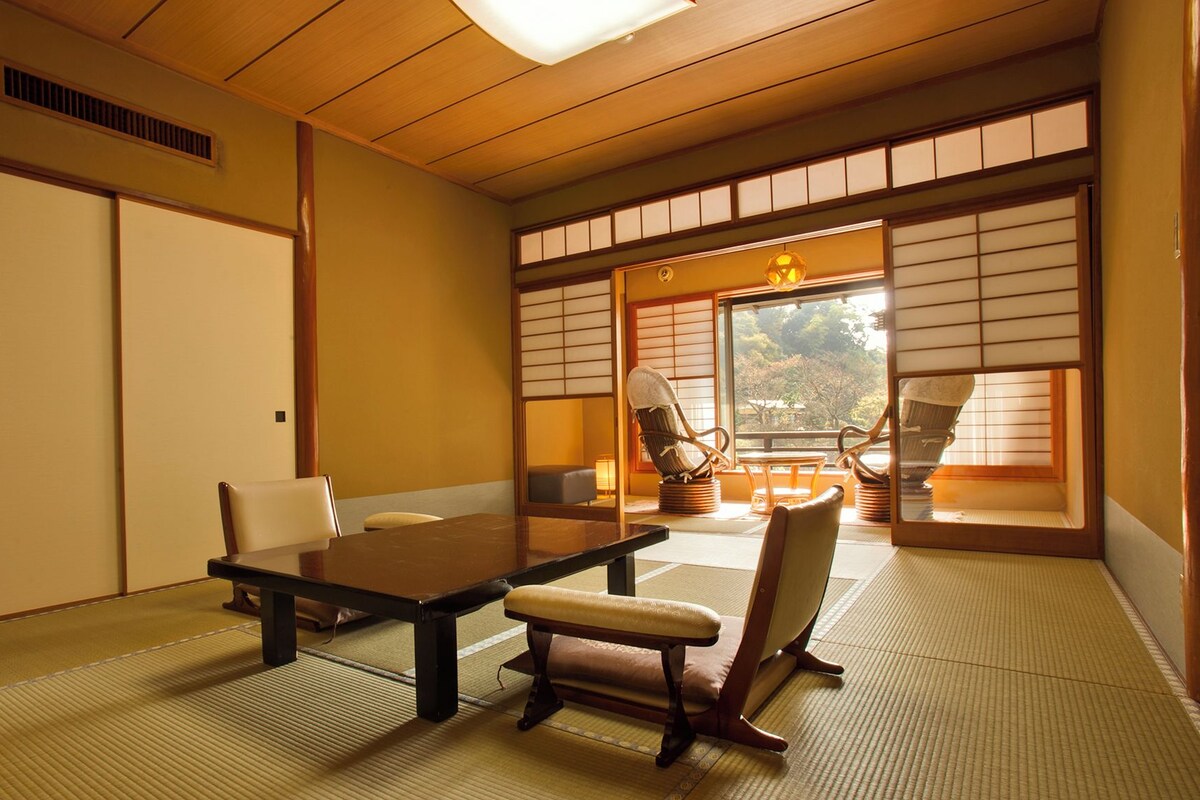 Um quarto japonês tradicional com tatames, uma mesa baixa e cadeiras.