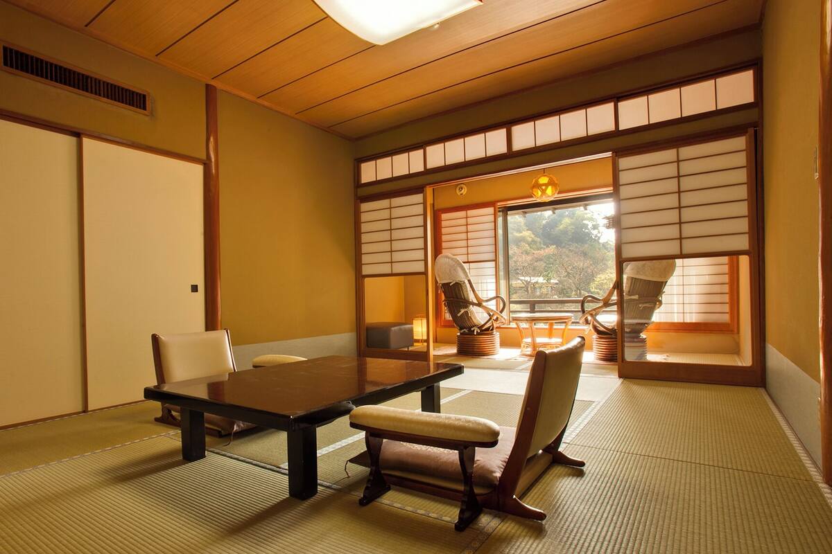 Um quarto japonês tradicional com tatames, uma mesa baixa e cadeiras.