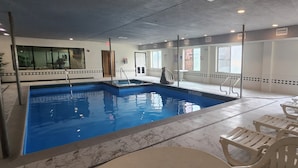 Piscina interna com água cristalina, cercada por espreguiçadeiras e piso revestido com azulejos.