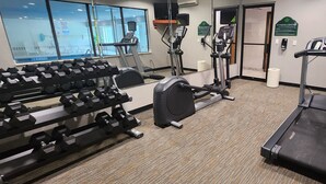 Uma academia com esteiras, halteres e equipamentos de exercício.