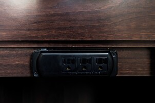 Superfície de madeira com painel de tomadas elétricas preto.