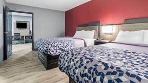 Quarto de hotel com duas camas, televisão, escrivaninha e uma cadeira.