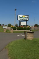 Placa do Budgetel Inn & Suites com vista clara da entrada e um gramado bem cuidado.