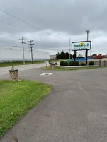 Uma estrada leva a um Budgettel Inn & Suites, com uma placa indicando uma área de estacionamento.