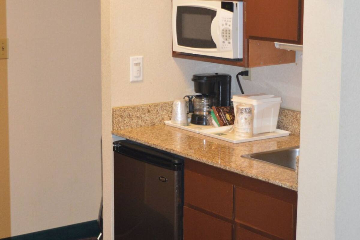 Uma cozinha compacta equipada com micro-ondas, cafeteira e máquina de lavar louça.