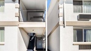 Um edifício com vários andares, uma escadaria central, paredes externas e janelas.