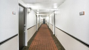 Corredor de hotel com portas numeradas 109 e 110, piso carpetado e paredes brancas.