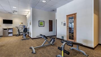 Centro de ginástica do hotel, com aparelhos de cardio, estações de musculação e uma televisão.