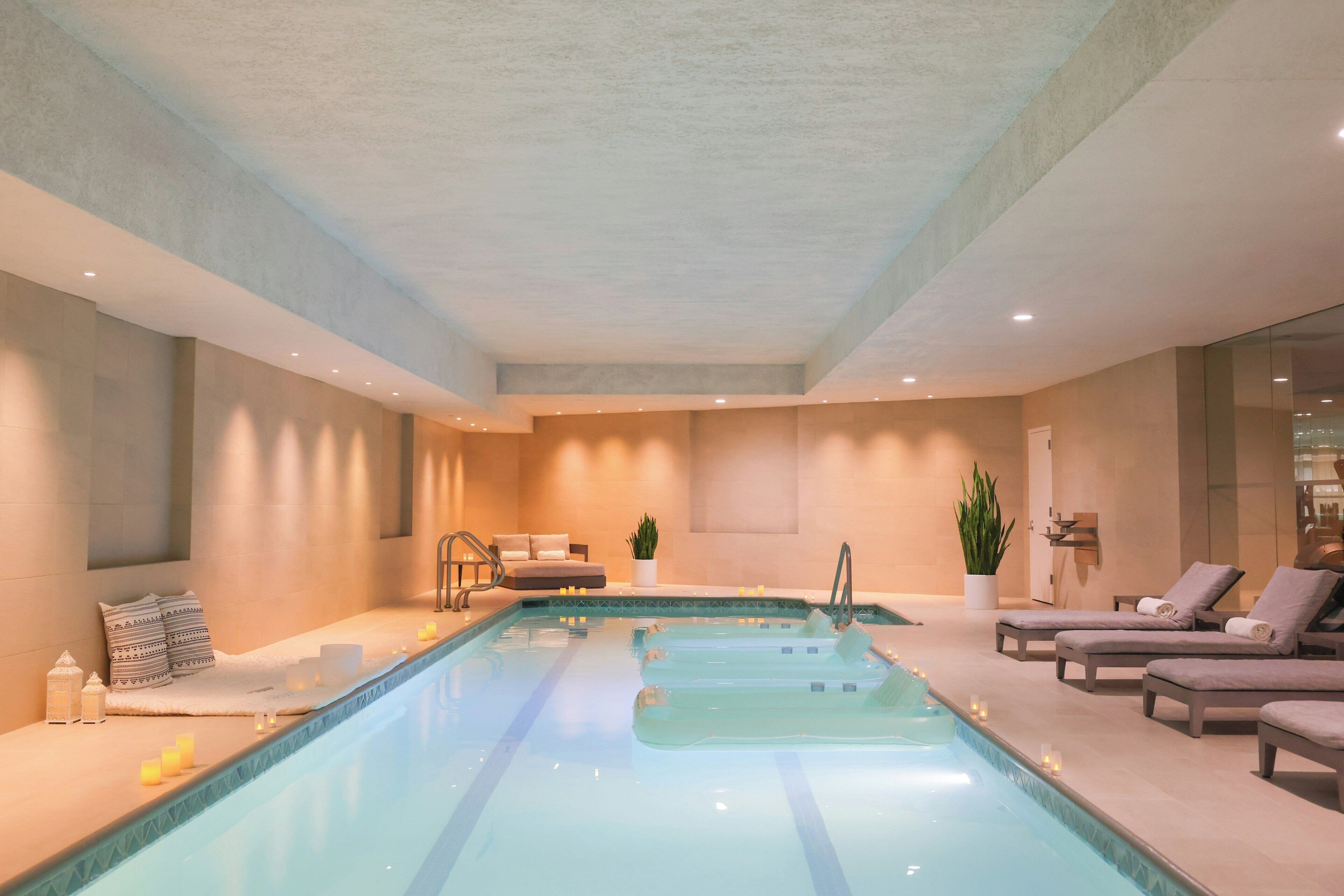 Piscina interior moderna com espreguiçadeiras e área de estar.