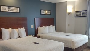 Duas camas de casal com cabeceiras de madeira, roupa de cama branca e uma parede de destaque azul.