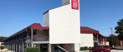 Um Red Roof Inn com telhado vermelho, paredes brancas e uma placa na fachada.