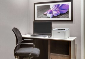 Um espaço de trabalho com computador, impressora e cadeira.