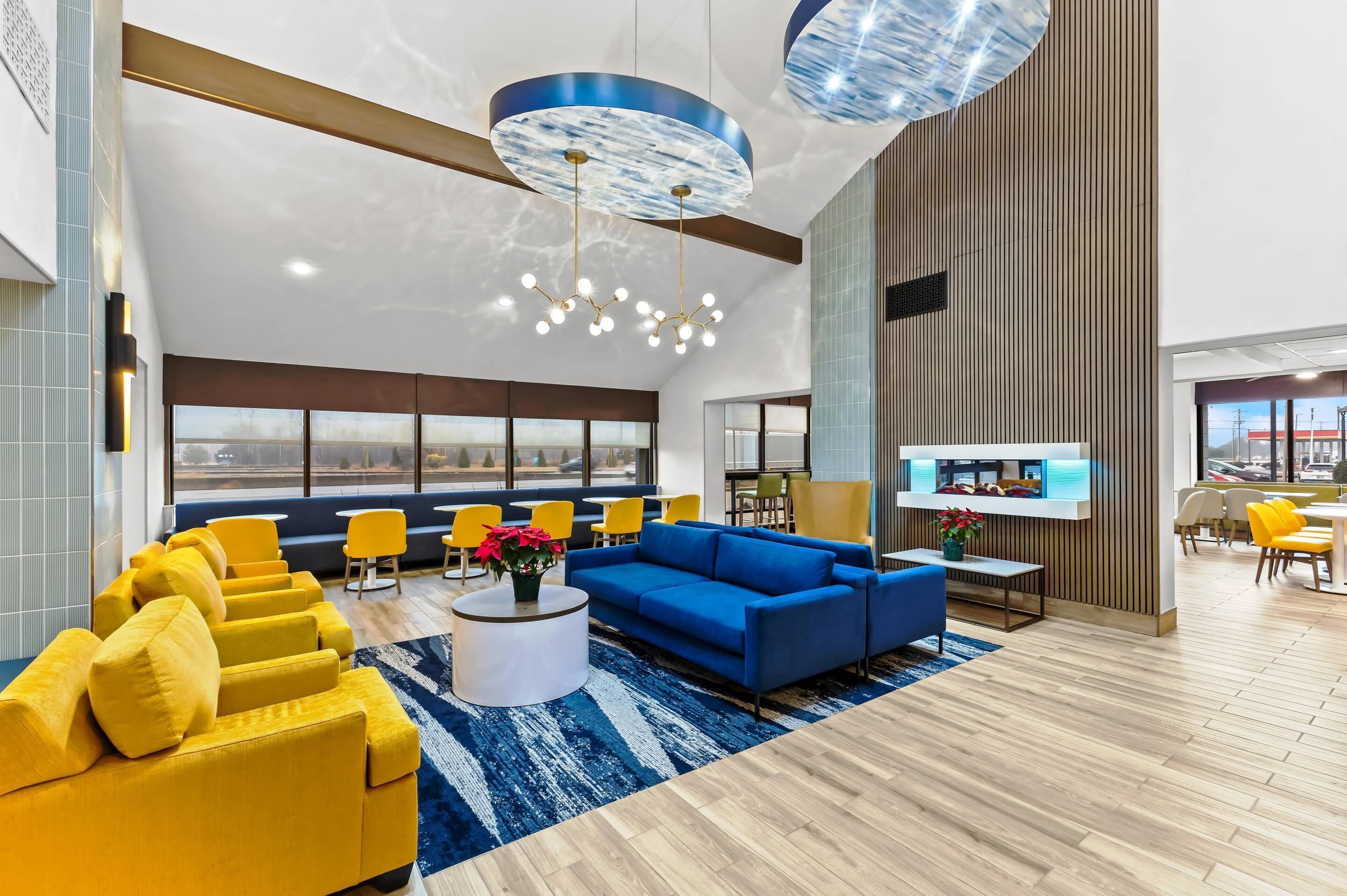 Um lobby moderno com áreas de estar, uma mesa de centro com flores e uma grande janela com vista.