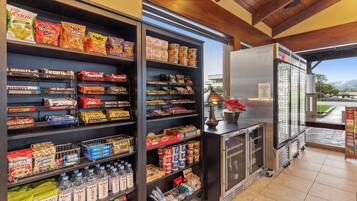 Espaço de exposição com lanches e bebidas, incluindo opções como salgadinhos, biscoitos e refrigerantes.