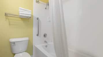 Um banheiro com vaso sanitário branco, banheira com cortina de chuveiro e porta-toalhas com toalhas dobradas.