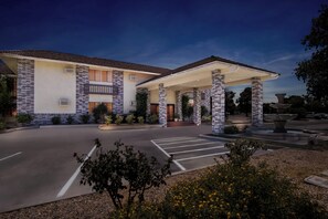 Um edifício de dois andares com entrada coberta e um acesso com paisagismo.